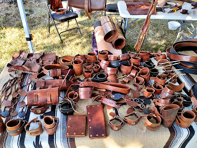 Leather goods spread across the table like a cowboy's dream buffet. Each belt, holster, and wallet carries the rich aroma of craftsmanship and durability.