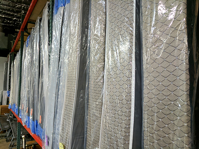 Mattresses lined up like dominos, each wrapped and waiting. Someone's perfect night's sleep is hiding in this practical forest.