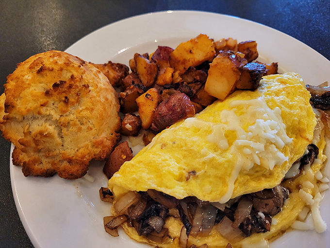 This isn't just breakfast – it's morning salvation in the form of a perfect omelet, crispy potatoes, and a biscuit that deserves its own fan club.