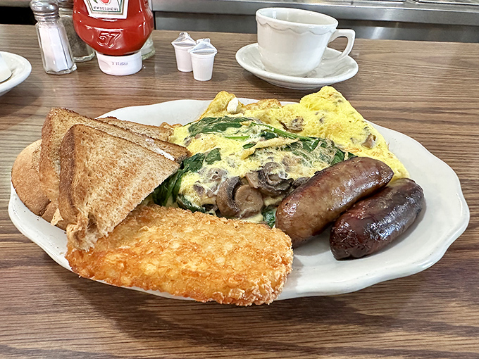 An omelet that's had everything but the kitchen sink thrown in, flanked by sausages standing guard like delicious sentinels.