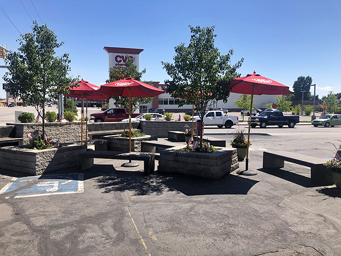 Red umbrellas provide shade for the sacred ritual of burger consumption, with Utah's majestic mountains standing guard in the background.