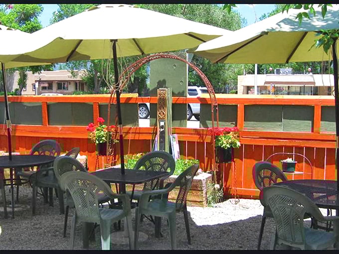 The patio's orange fence and cream umbrellas create an oasis of calm. This is where breakfast dreams and afternoon conversations find their perfect setting.