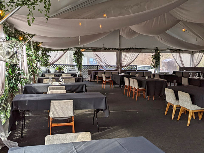 The outdoor dining tent transforms into an elegant garden party, with flowing fabrics and greenery creating an atmosphere of casual luxury.
