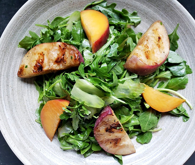 This salad with grilled peaches isn't just eating your greens – it's treating your greens to a summer vacation.