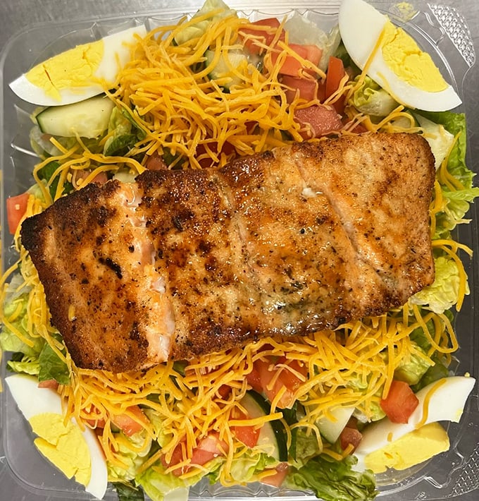 A perfectly seasoned salmon fillet resting on a bed of fresh salad&mdash;because sometimes even soul food lovers need a lighter option (that's still heavy on flavor).
