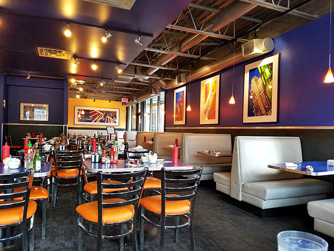 Modern art meets comfort food in this dining room, where blue walls and orange chairs create the perfect backdrop for breakfast bliss.