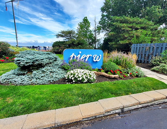 The Pier W sign, nestled among flowers like a blue jewel in a garden setting. Nature's own welcome committee for hungry visitors.