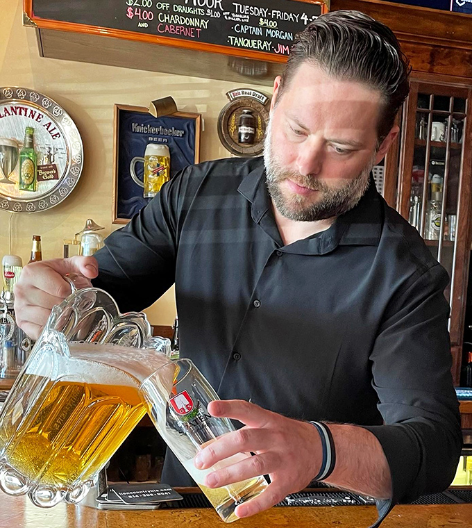 The image shows a staff member carefully pouring a beer. That focused expression is the look of someone who takes your enjoyment seriously.