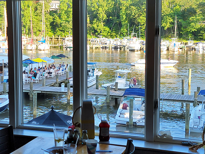 Floor-to-ceiling windows frame views of the marina, boats, and outdoor diners living their best waterside dining life.