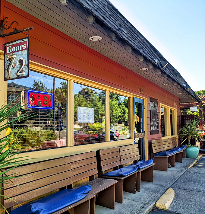 Blue benches await the breakfast faithful outside The Breadboard, where the "Open" sign rarely disappoints those seeking morning salvation.