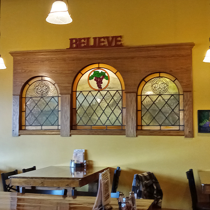 Stained glass featuring grapes that remind you this place takes its wine as seriously as that "Believe" sign suggests you should.