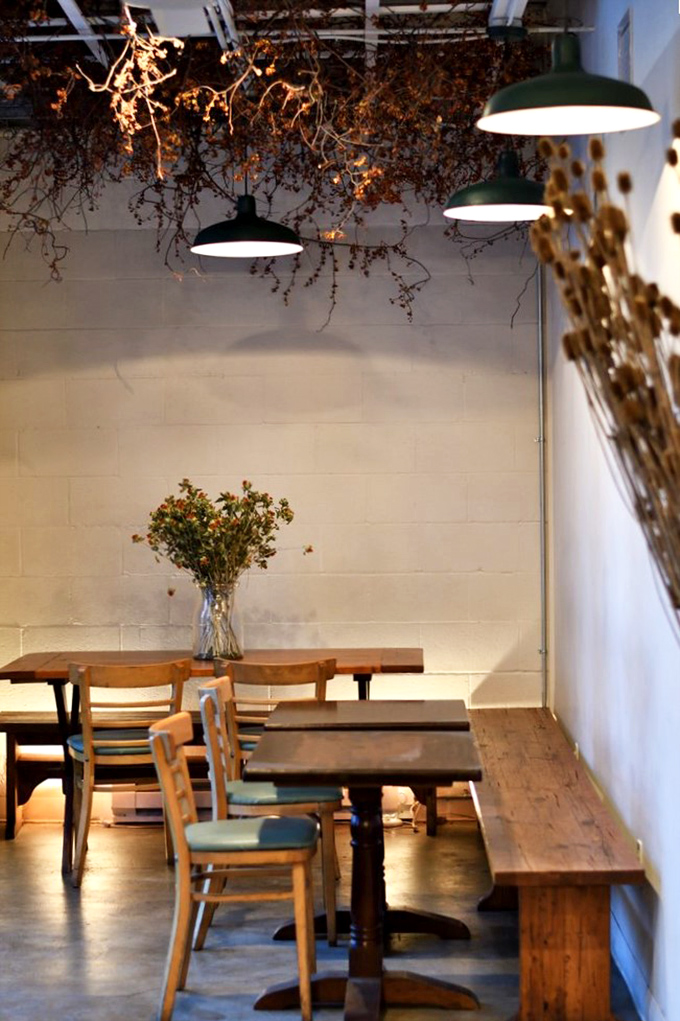 Dried botanicals hang from the ceiling like an upside-down garden, creating an atmosphere that's equal parts rustic charm and modern sensibility.