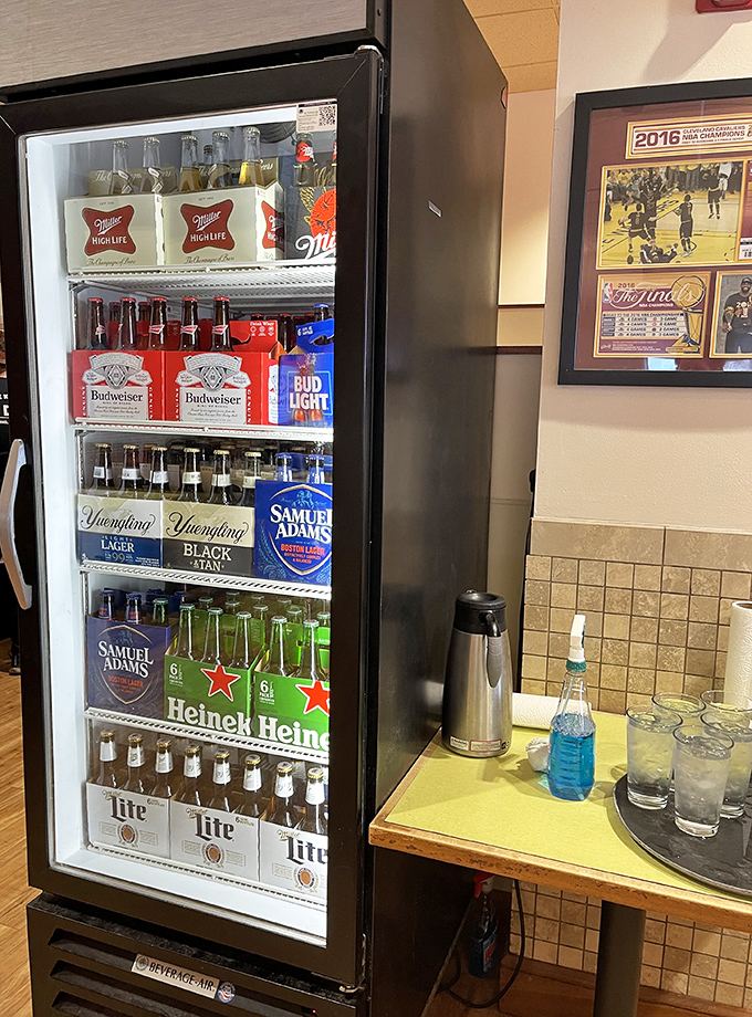 The beverage cooler—where decisions between local brews and national favorites become philosophical quandaries. Cleveland sports memorabilia stands guard nearby.