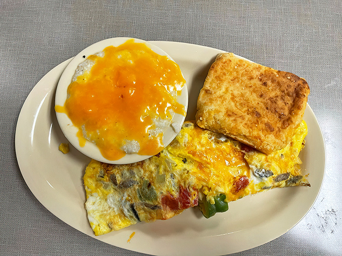 Breakfast perfection: cheesy grits, a golden omelet studded with vegetables, and a biscuit that deserves its own fan club.