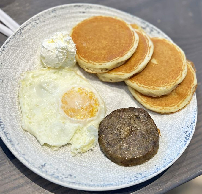 The classic breakfast plate &ndash; golden pancakes, perfectly fried egg, and sausage &ndash; proves sometimes the simplest combinations are the most satisfying.