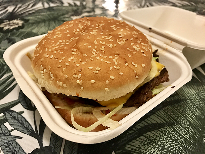 The classic burger in its foam throne&mdash;sesame seeds scattered like confetti celebrating the perfect union of beef, cheese, and fresh toppings.