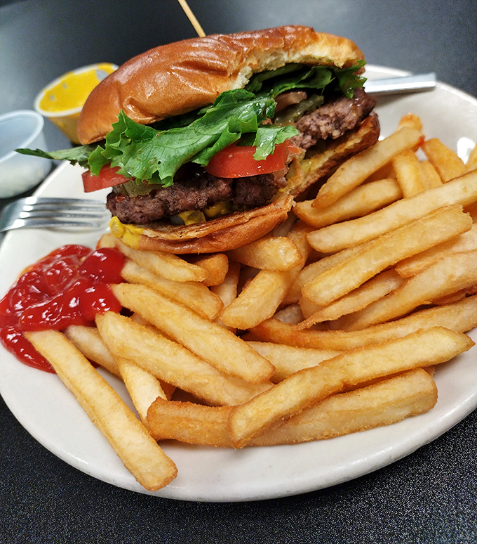A burger that requires two hands and a strategy, accompanied by a golden army of crispy fries&mdash;simple food executed with the confidence of experience.