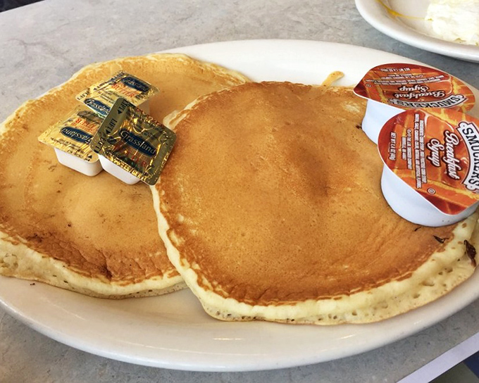 Pancakes so perfectly golden they belong in Fort Knox. Those butter packets are just waiting for their moment of melty glory.