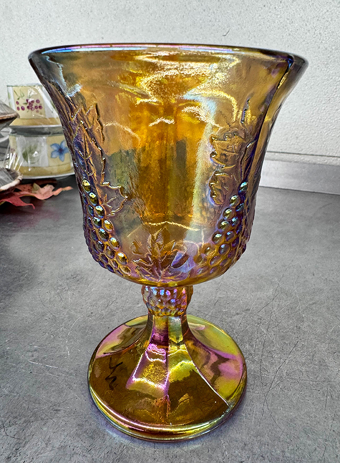This amber carnival glass goblet gleams with iridescent memories of dinner parties past, waiting for its next toast.