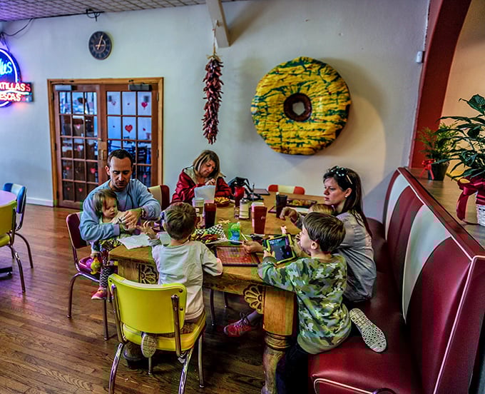 Families gather around mismatched tables because great food brings people together regardless of matching furniture or formal settings.