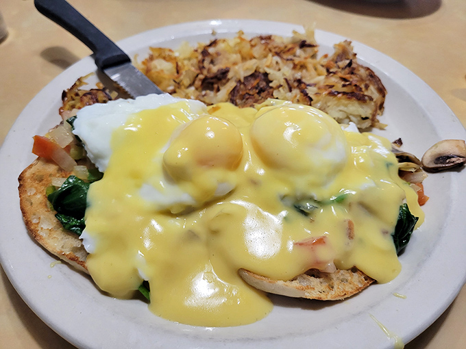 Hollandaise cascading over poached eggs like yellow velvet&mdash;this Benedict isn't just breakfast, it's performance art with hash browns as the supporting cast.