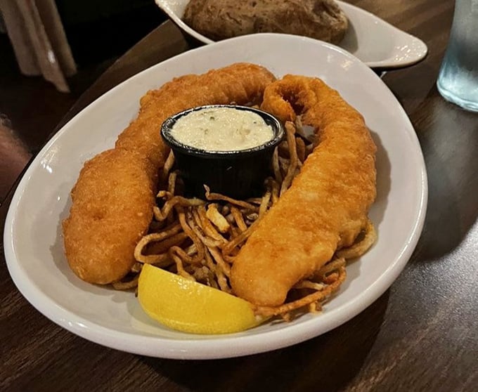 Fish and chips that could make a Londoner homesick. The golden batter shatters with each bite, revealing tender fish beneath&mdash;a textural masterpiece.
