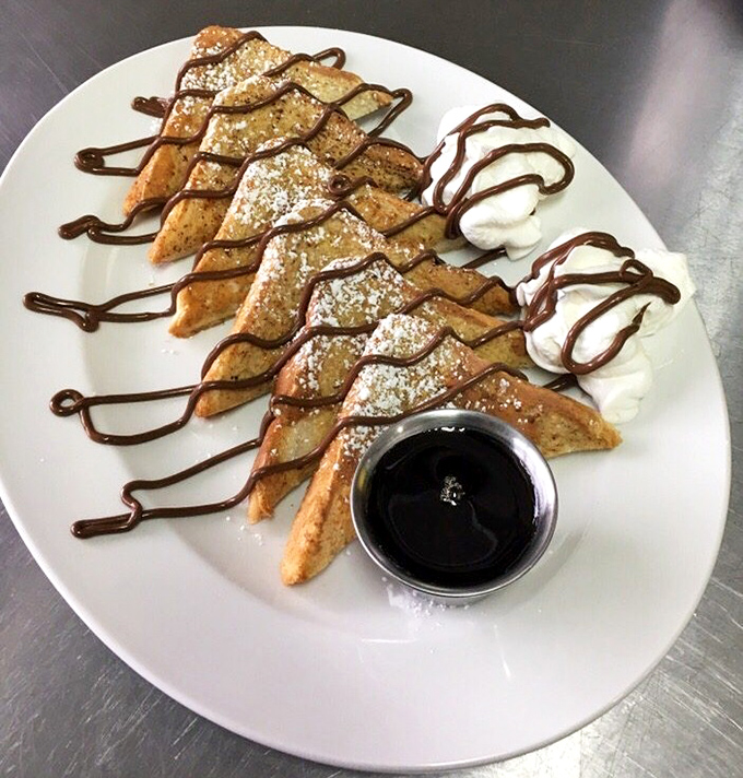 French toast triangles drizzled with chocolate and dusted with powdered sugar – breakfast that boldly crosses into dessert territory without apology.