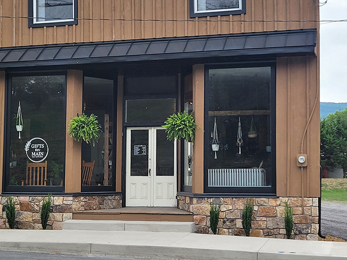 Gifts on Main showcases handcrafted treasures behind large windows, where hanging plants frame doorways welcoming visitors to explore local artistry.