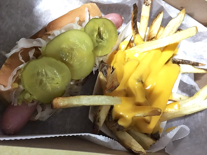 A study in contrasts: crisp pickle slices, tangy sauerkraut, and golden cheese fries that turn a simple hot dog into a celebration.