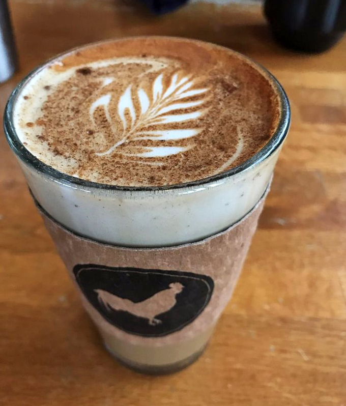 Latte art so pretty you almost don't want to drink it. Almost. The rooster logo reminds you this is serious morning business.