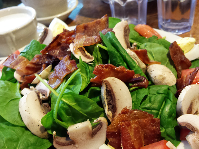 This isn't just a salad—it's a masterpiece of fresh spinach, mushrooms, crispy bacon, and vegetables that might actually make you forget about the cheesecake in the display case.