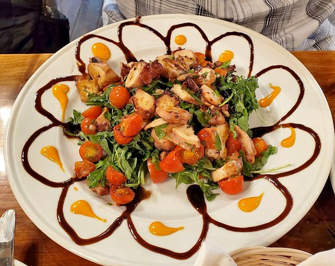 An octopus salad that transforms the intimidating into the irresistible, artfully presented with colorful tomatoes and a decorative sauce that's equal parts flavor and flair.