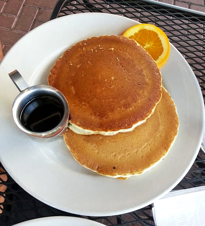 Golden pancakes stacked like edible frisbees, with a side of syrup that's just waiting to create the breakfast equivalent of Niagara Falls.