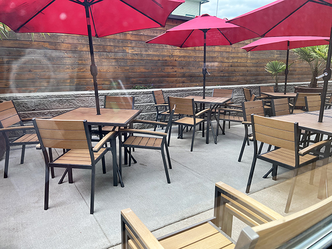 The outdoor patio, where red umbrellas stand guard against both sun and judgment for ordering that second cinnamon roll. Fresh air aids digestion, right?