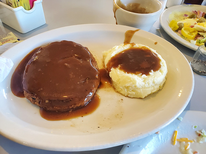 Salisbury steak swimming in gravy with mashed potatoes standing by&mdash;comfort food that hugs you from the inside out.