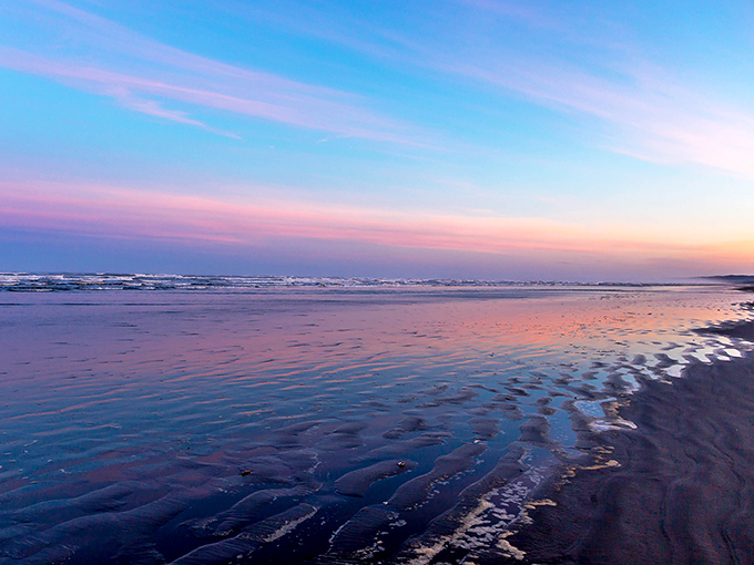Low tide transforms the beach into a mirror for the sky's pastel performance&mdash;nature's way of doubling the beauty without charging extra admission.