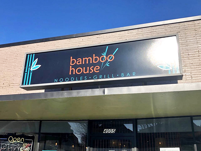 The sleek signage announces "Noodles &bull; Grill &bull; Bar" with understated confidence&mdash;three simple words that promise a world of flavor behind those doors.