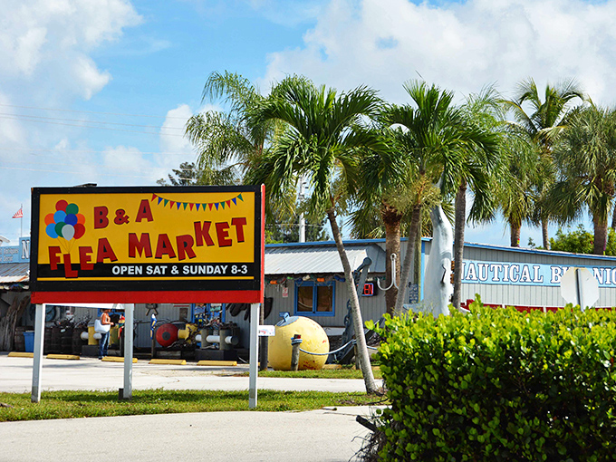 The cheerful B&A Flea Market sign stands sentinel among palm trees, beckoning weekend treasure hunters with its primary-colored simplicity.