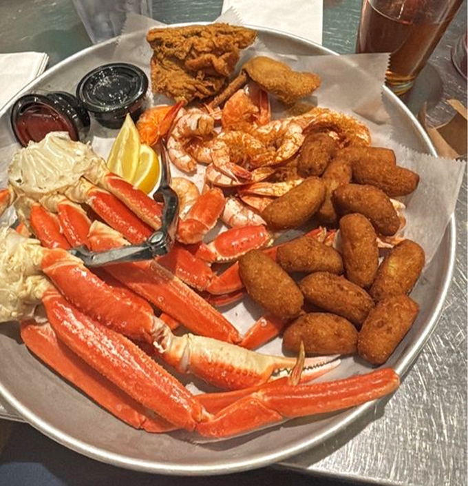 Snow crab legs, peel-and-eat shrimp, and hush puppies create a seafood symphony on a metal platter. This isn't just dinner&mdash;it's an event.
