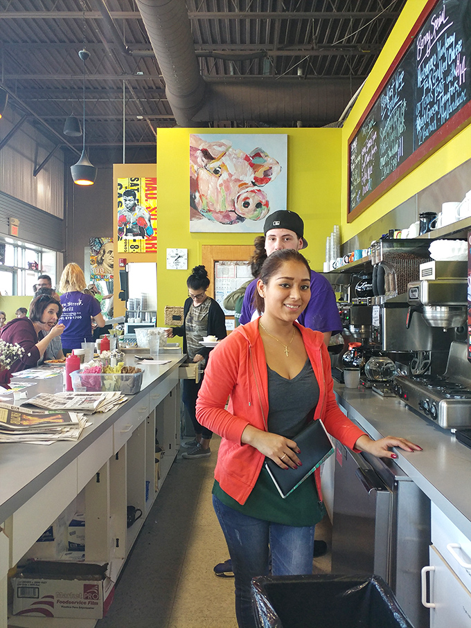 Behind every great breakfast is a dedicated team. The bright yellow walls and colorful artwork create the perfect backdrop for morning culinary magic.