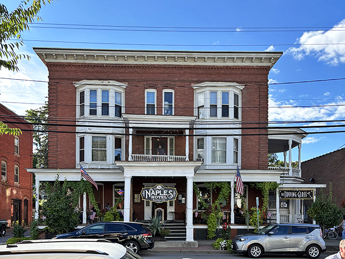 The Naples Hotel stands proudly on Main Street, its historic brick facade and welcoming porch promising comfortable beds and small-town hospitality since the 19th century.