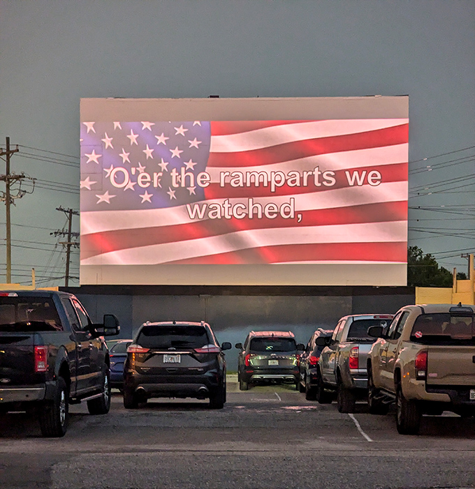As twilight falls, cars gather before the massive screen, where American traditions are celebrated in more ways than one.