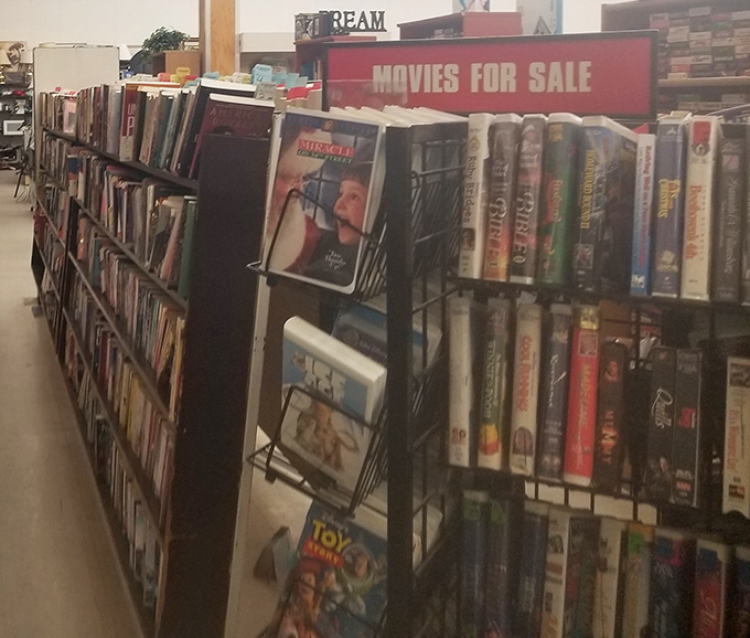 The VHS section: a nostalgic time capsule where "Be Kind, Rewind" stickers remind us of simpler entertainment eras.