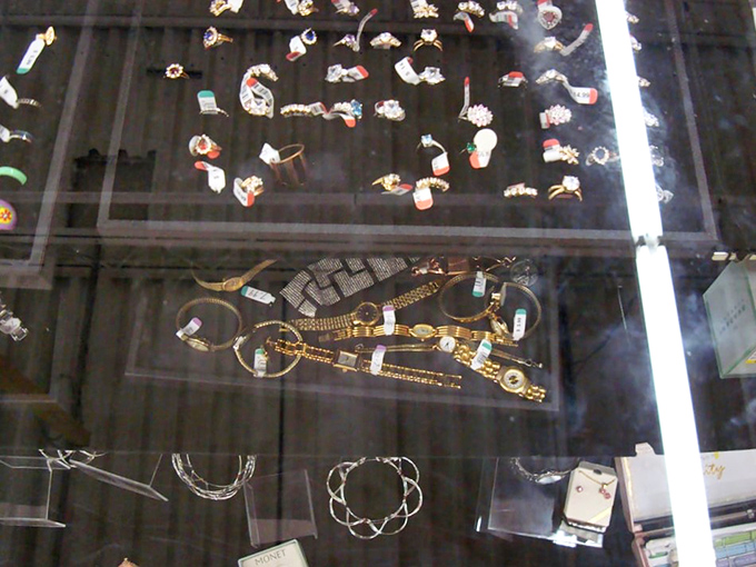 Behind glass, jewelry pieces wait like supporting actors ready for their spotlight moment on someone's wrist or neckline.