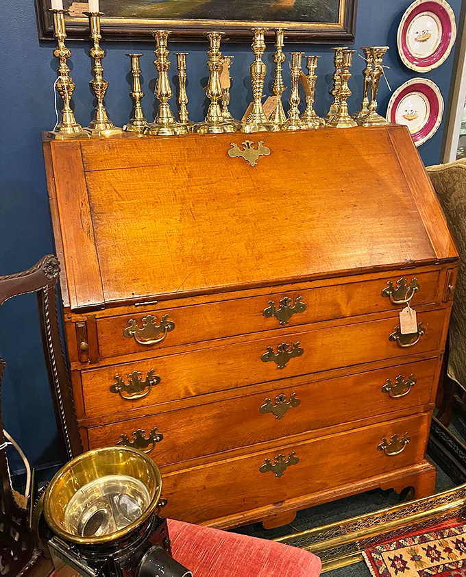 A slant-front desk topped with brass candlesticks standing at attention like soldiers, ready to illuminate your next great letter or memoir.