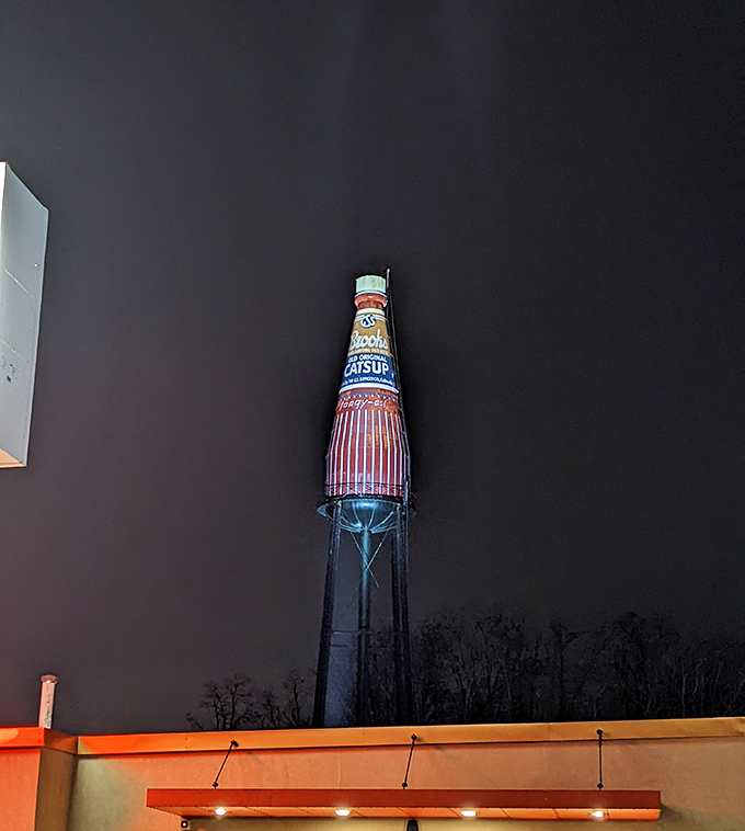 By night, the illuminated bottle glows against the darkness, a beacon for road-trippers and proof that the best attractions shine at any hour.