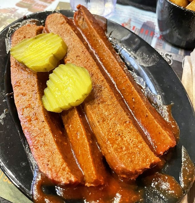 Barbecue sausages lounging in their own juices like they're at a smoky spa, with pickle chips standing by for that perfect tangy counterpoint.