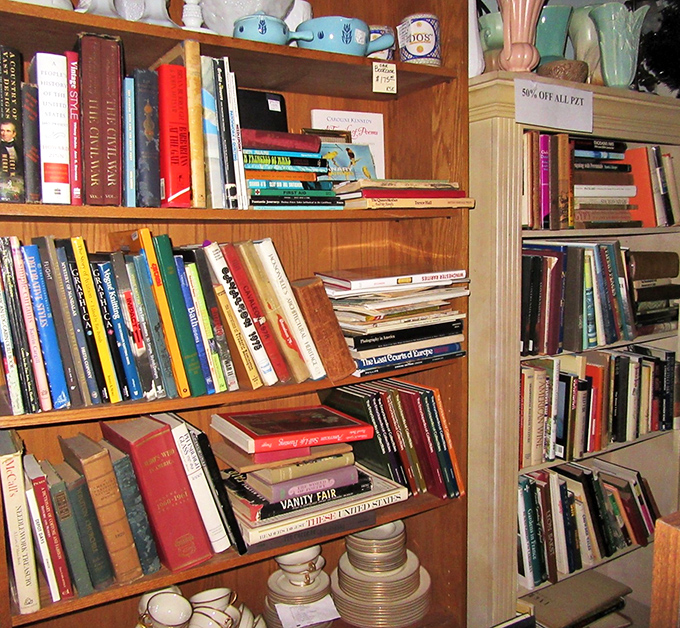 Books stacked with care &ndash; from classic literature to vintage cookbooks &ndash; each spine representing someone's former favorite reading chair companion.