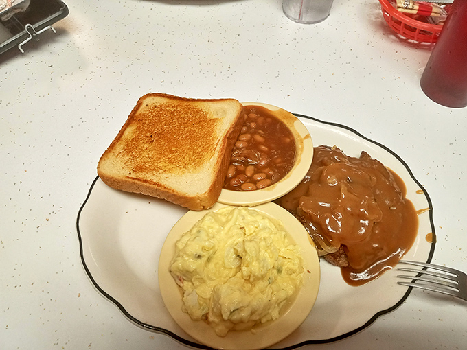 A humble plate of comfort featuring toast, potato salad, beans, and gravy-smothered meat&mdash;the kind of meal that makes you understand why diners endure.