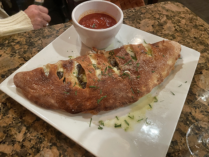 This calzone isn't just folded pizza&mdash;it's a self-contained pocket of joy with a side of marinara for essential dipping operations.
